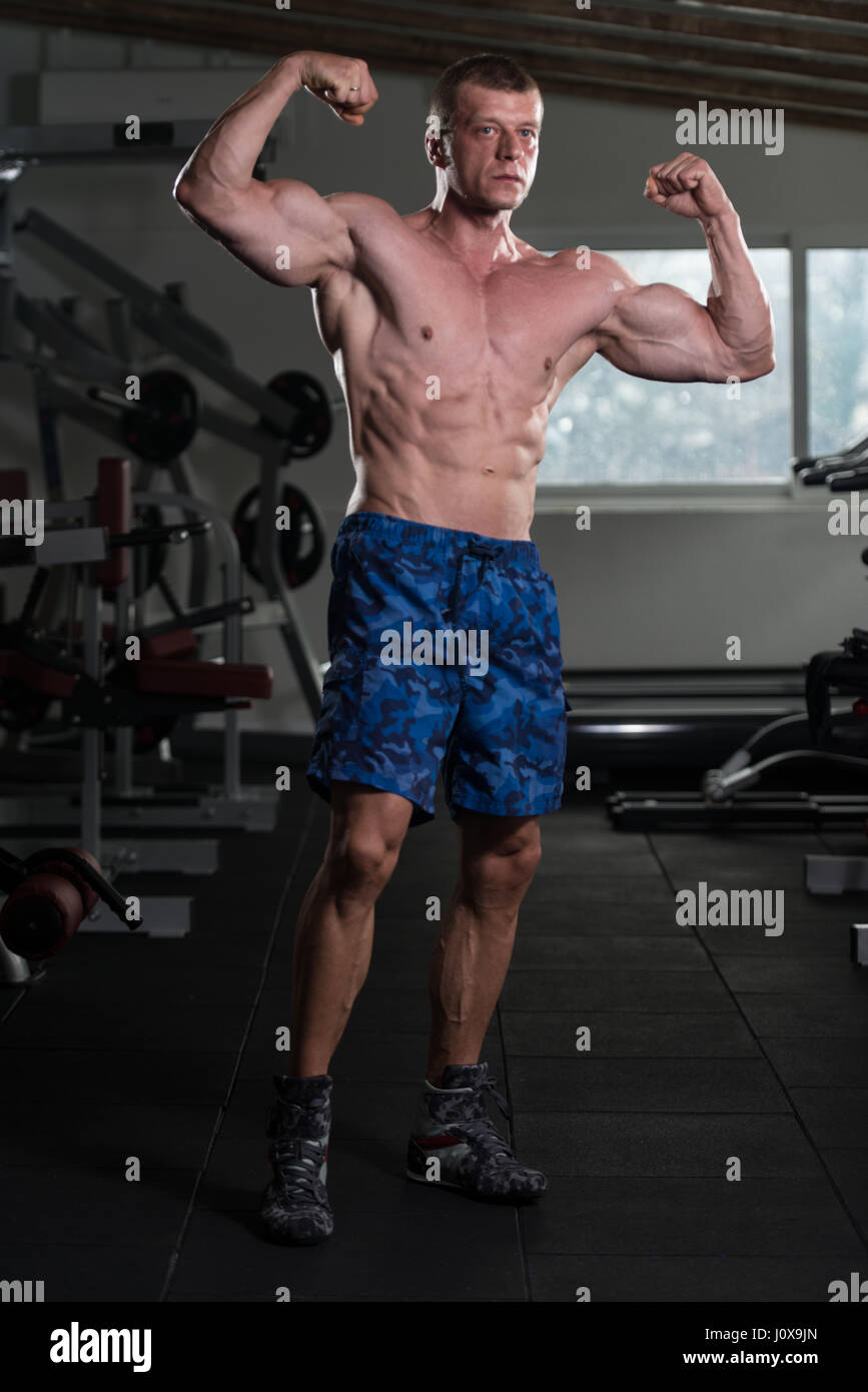 Healthy Man Standing Strong In The Gym And Flexing Muscles - Muscular ...