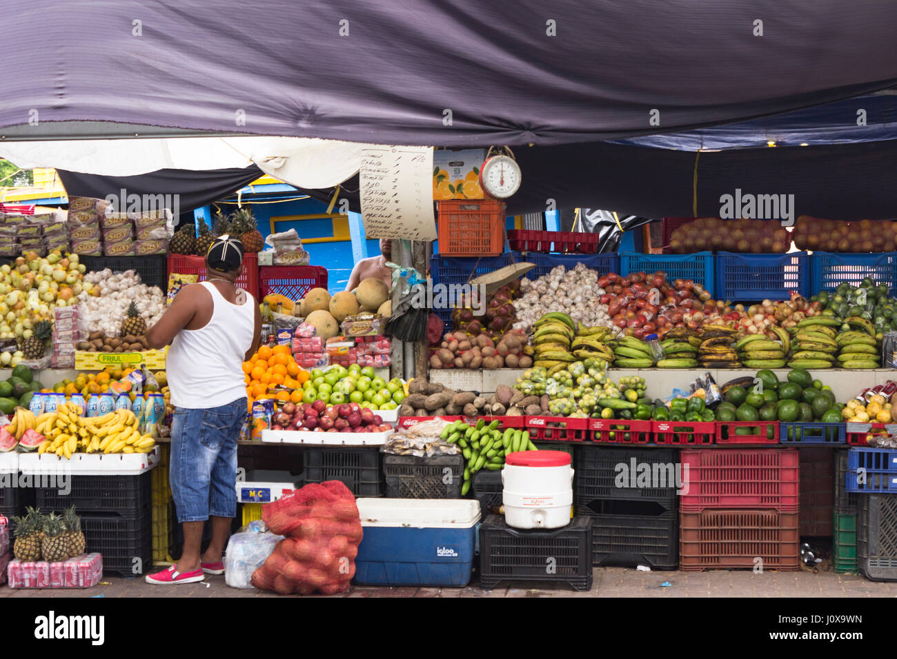 A vendor mans his produce stall in the floating market, Willemstad ...