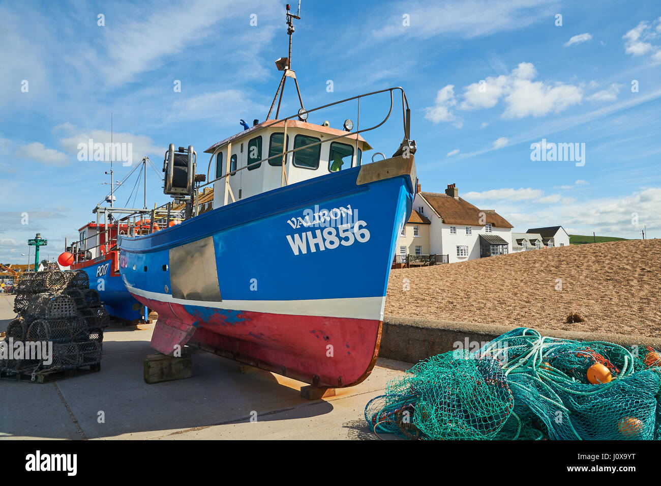 Colourful fishing boats left on the quayside in the Dorset seaside town ...