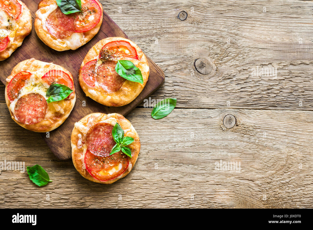 Italian mini pizzas with salami tomatoes cheese and basil for snack ...