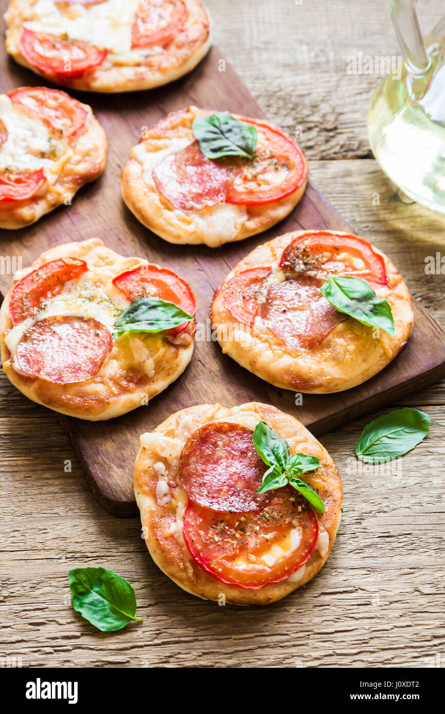 Italian mini pizzas with salami tomatoes cheese and basil for snack ...