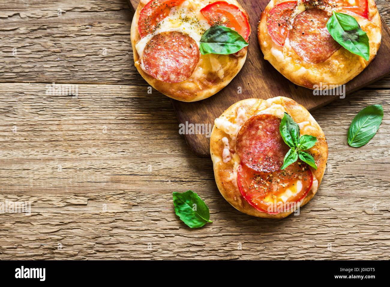 Italian mini pizzas with salami tomatoes cheese and basil for snack ...