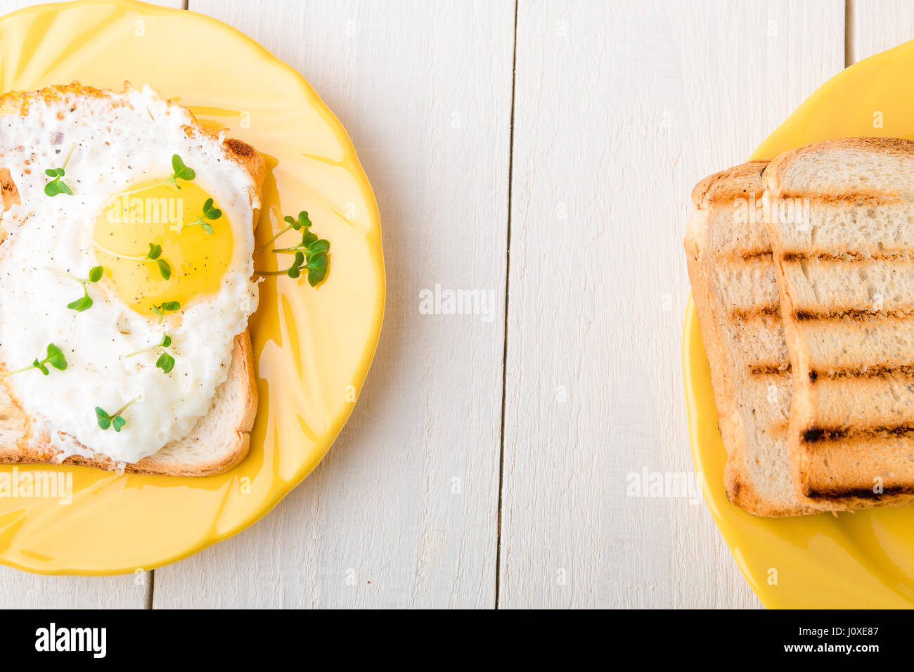 Toast with egg in yellow plate with Micro-greenery on white wooden ...