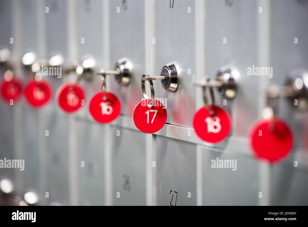 Row of metal lockers with locks, keys and numbered red tags in a sports ...