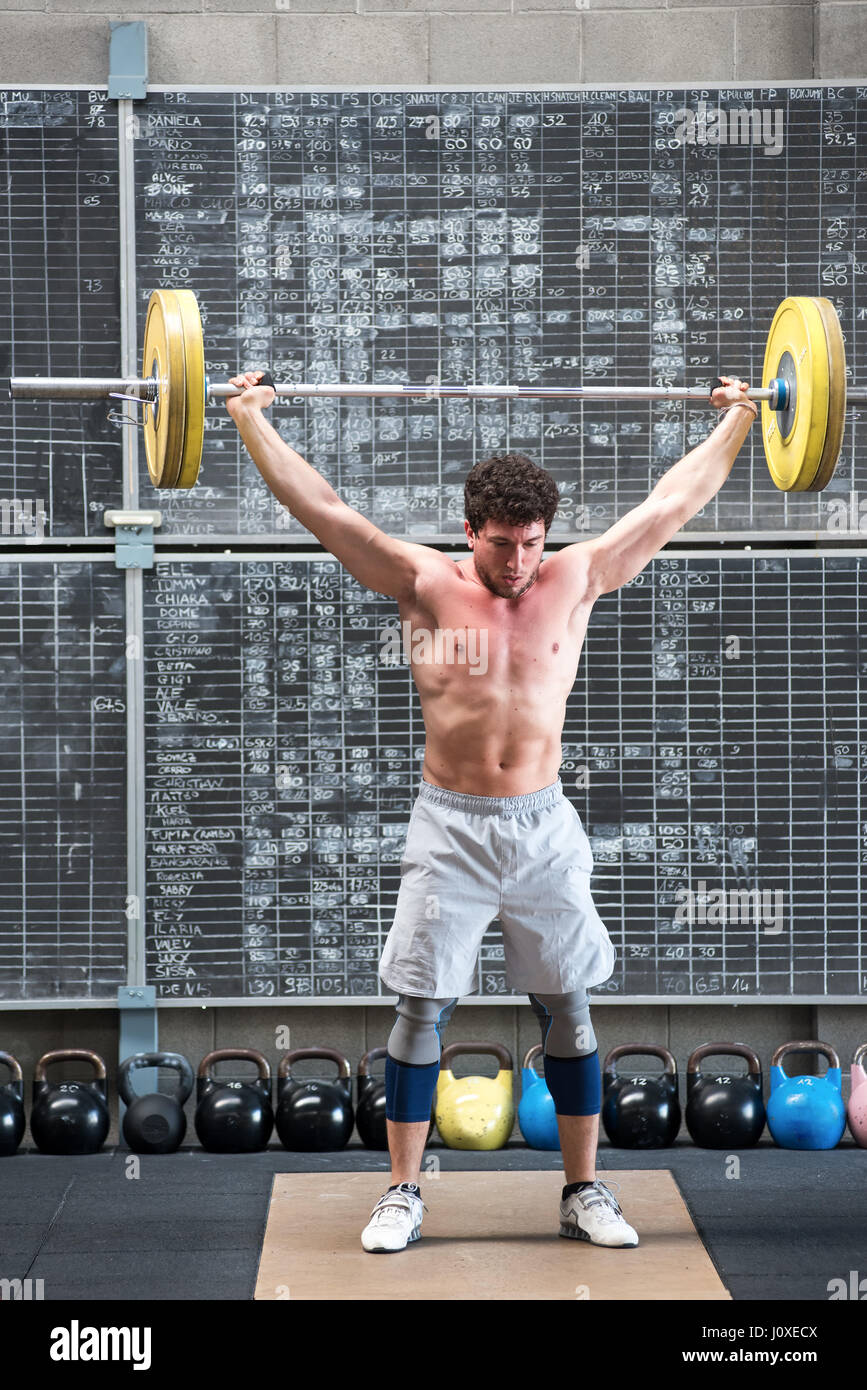Fit muscular weightlifter doing crossfit training doing a snatch and ...