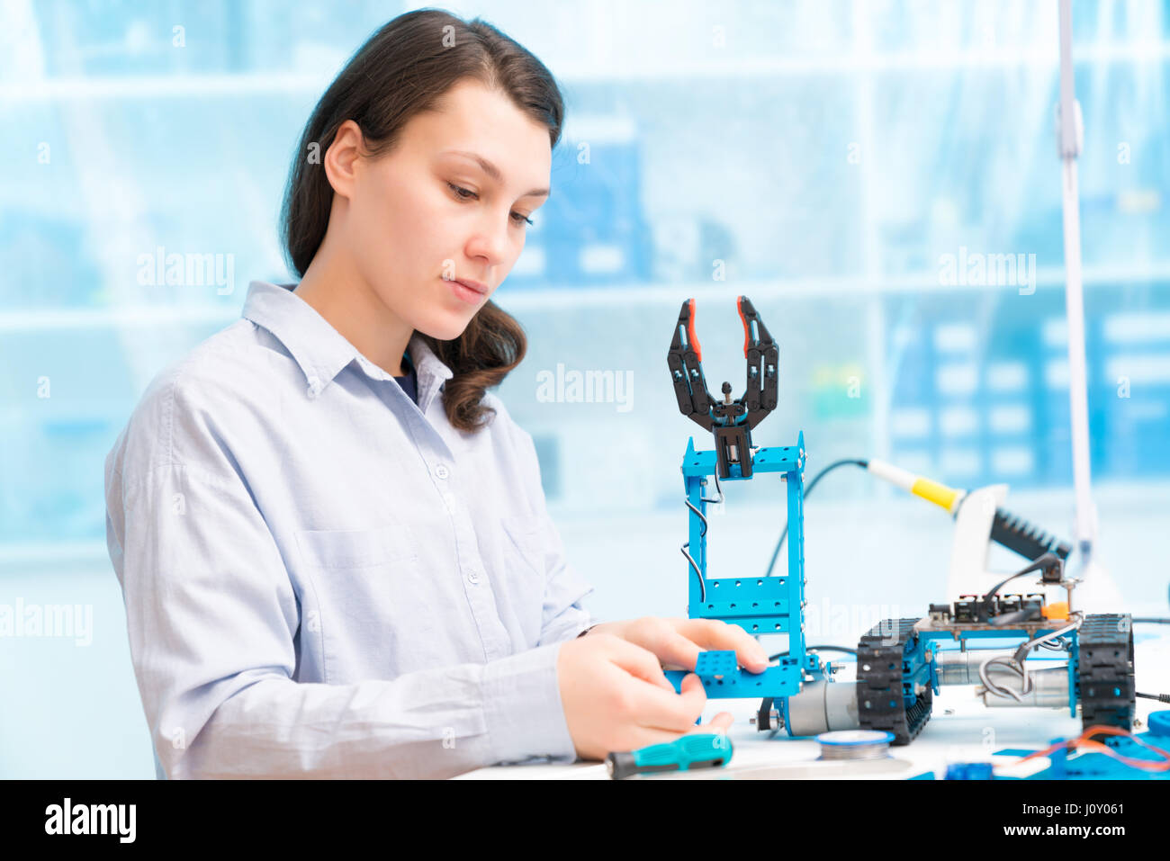Girl in robotics laboratory. Young woman technician repair roboter ...