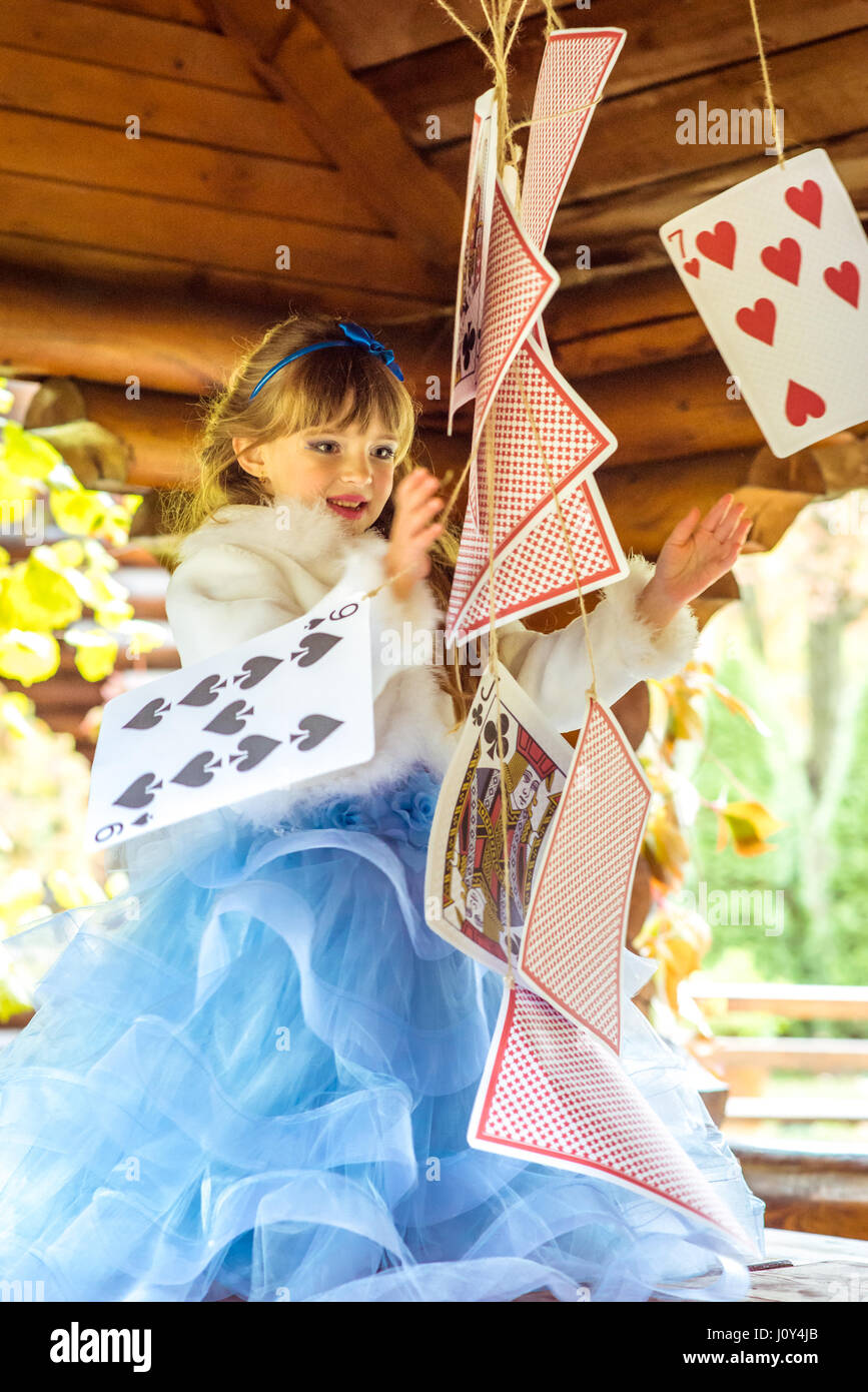 An little beautiful girl playing and dancing with large playing cards ...