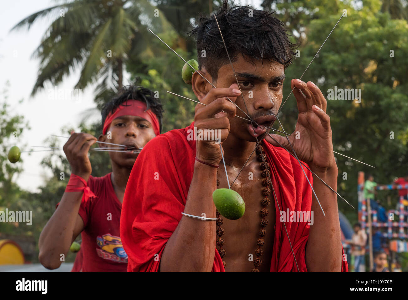 Young indian man with skewers through his cheeks at the Gajan and ...