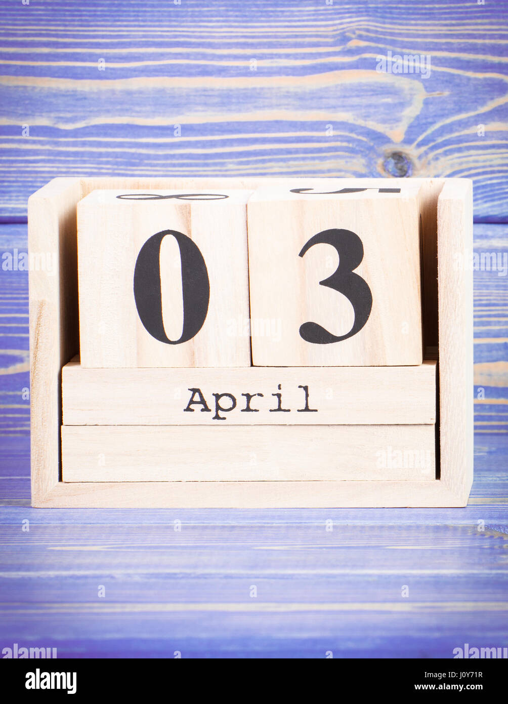 April 3rd. Date of 3 April on wooden cube calendar, purple board as ...