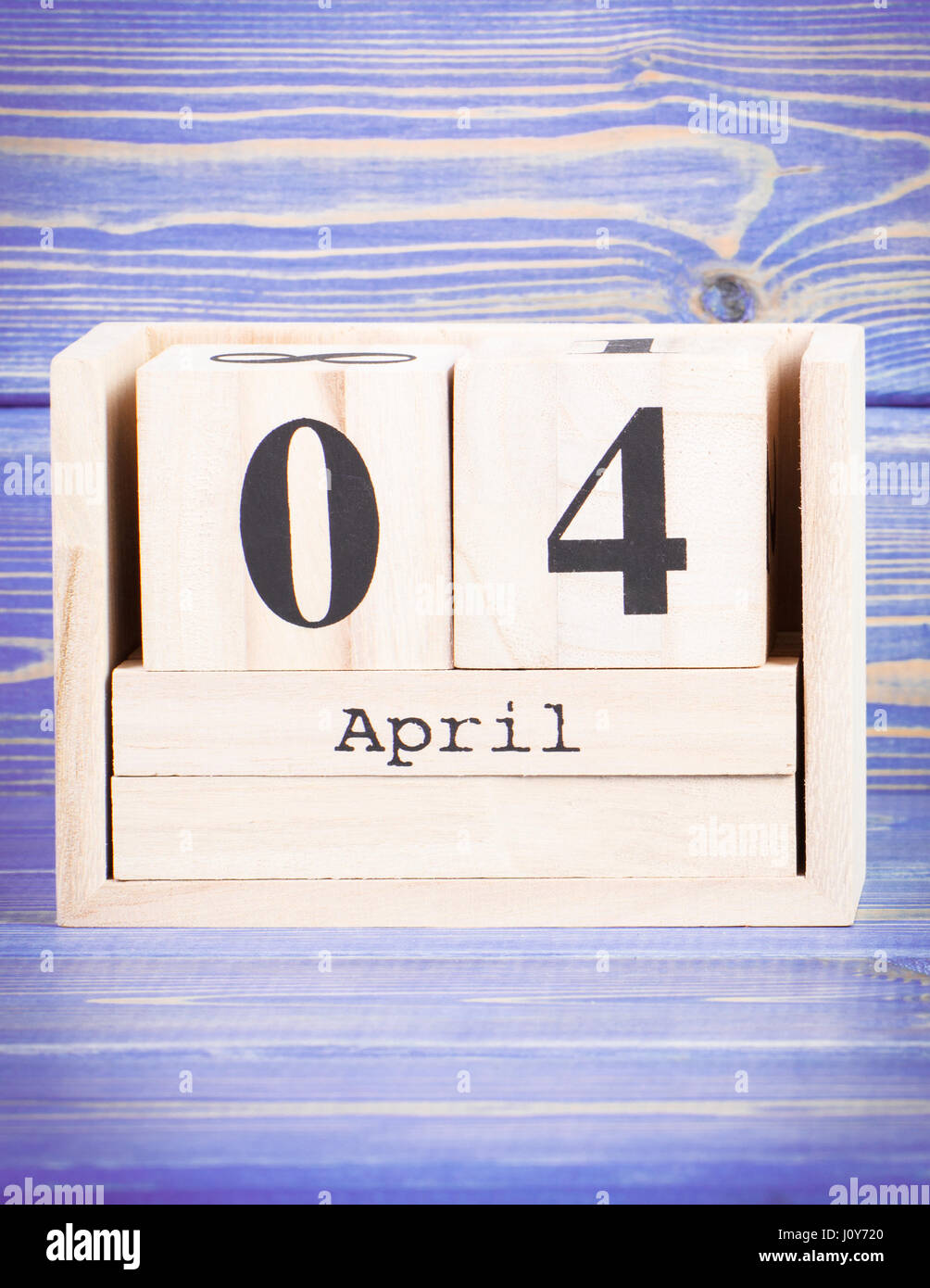 April 4th. Date of 4 April on wooden cube calendar, purple board as ...