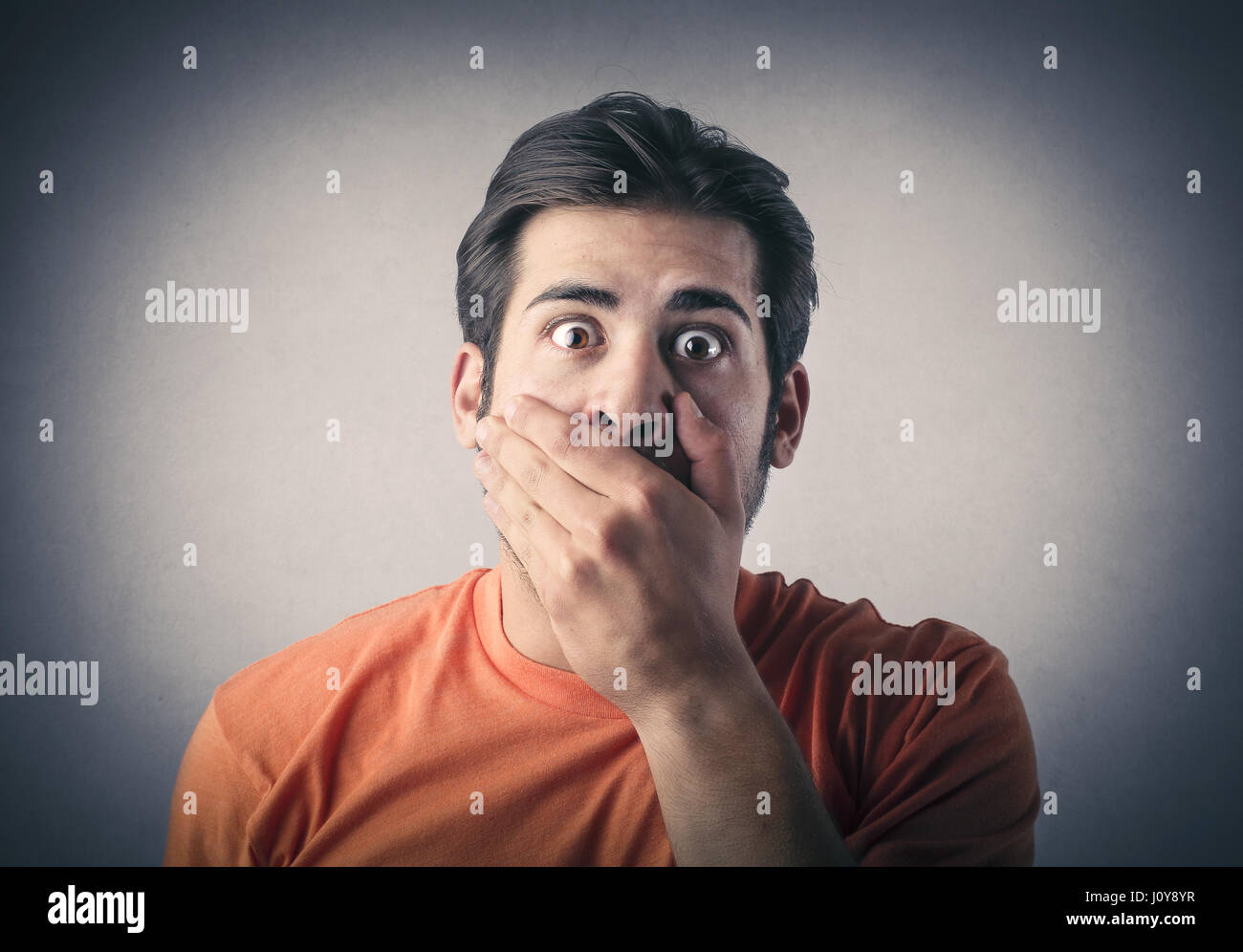 Scared man holding his mouth Stock Photo - Alamy