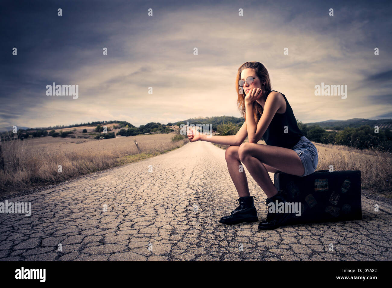 Woman hitchhiking while sitting on luggage Stock Photo - Alamy Woman hitchhiking while sitting on luggage Stock Photo - Alamy