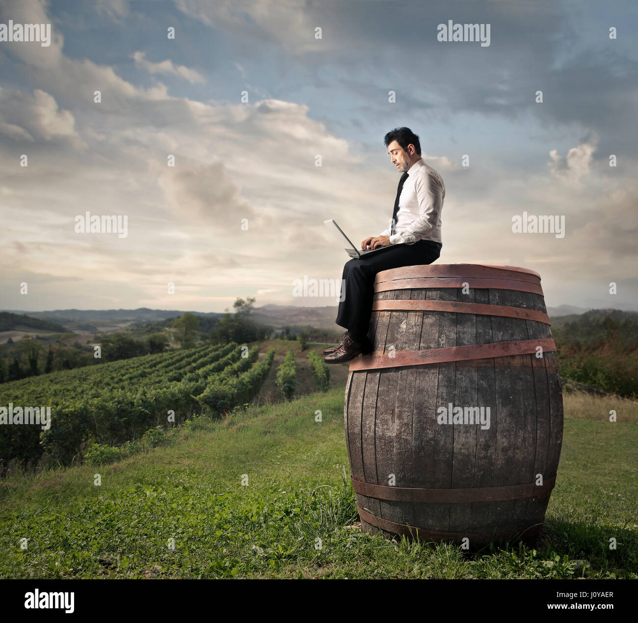 Businessman sitting on huge barrel Stock Photo - Alamy