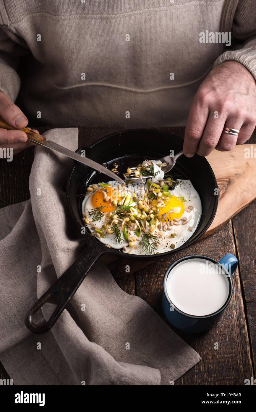 Eating scramble eggs on the wooden table vertical Stock Photo - Alamy