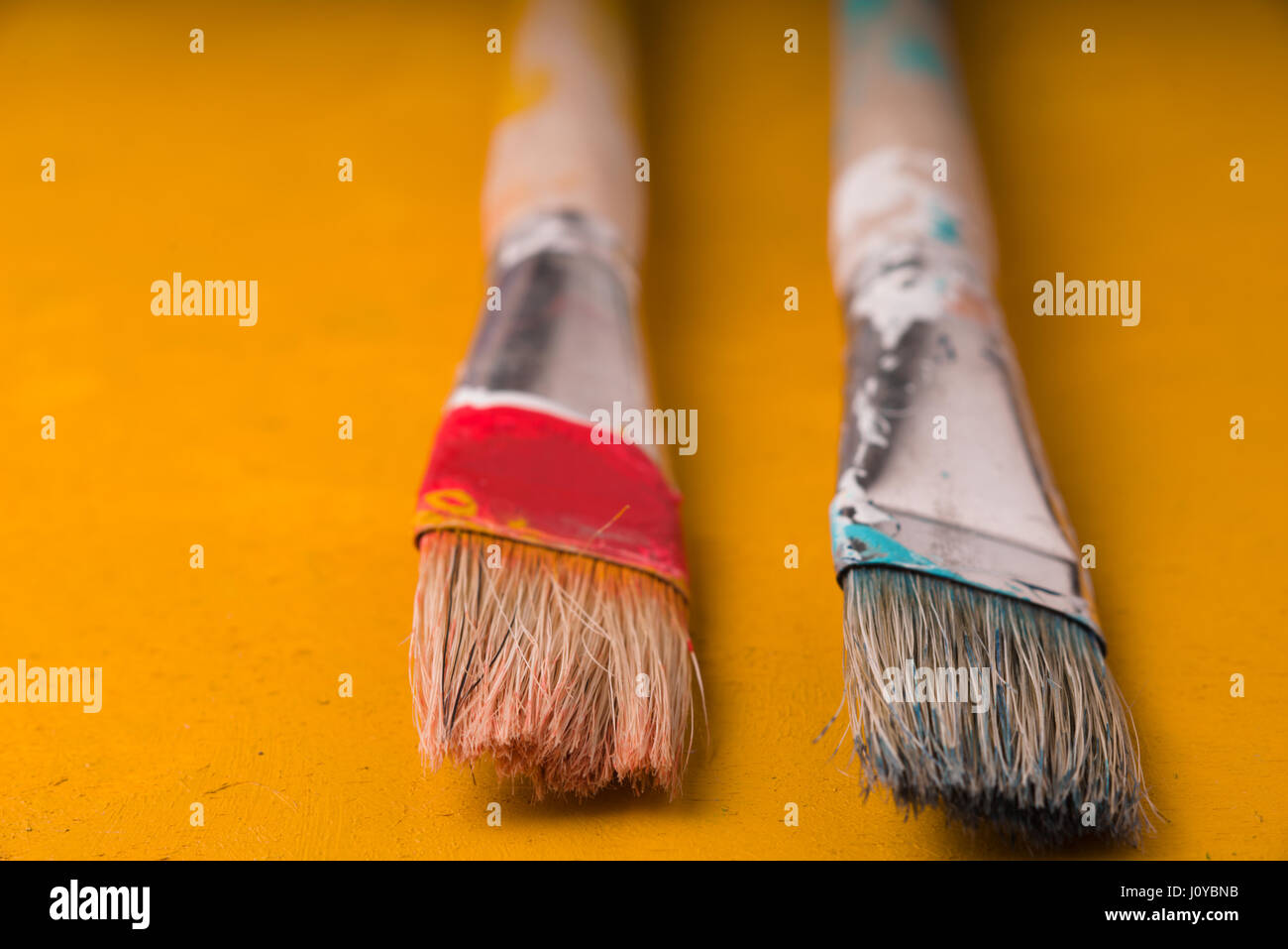 Two paint brushes on a yellow table Stock Photo - Alamy