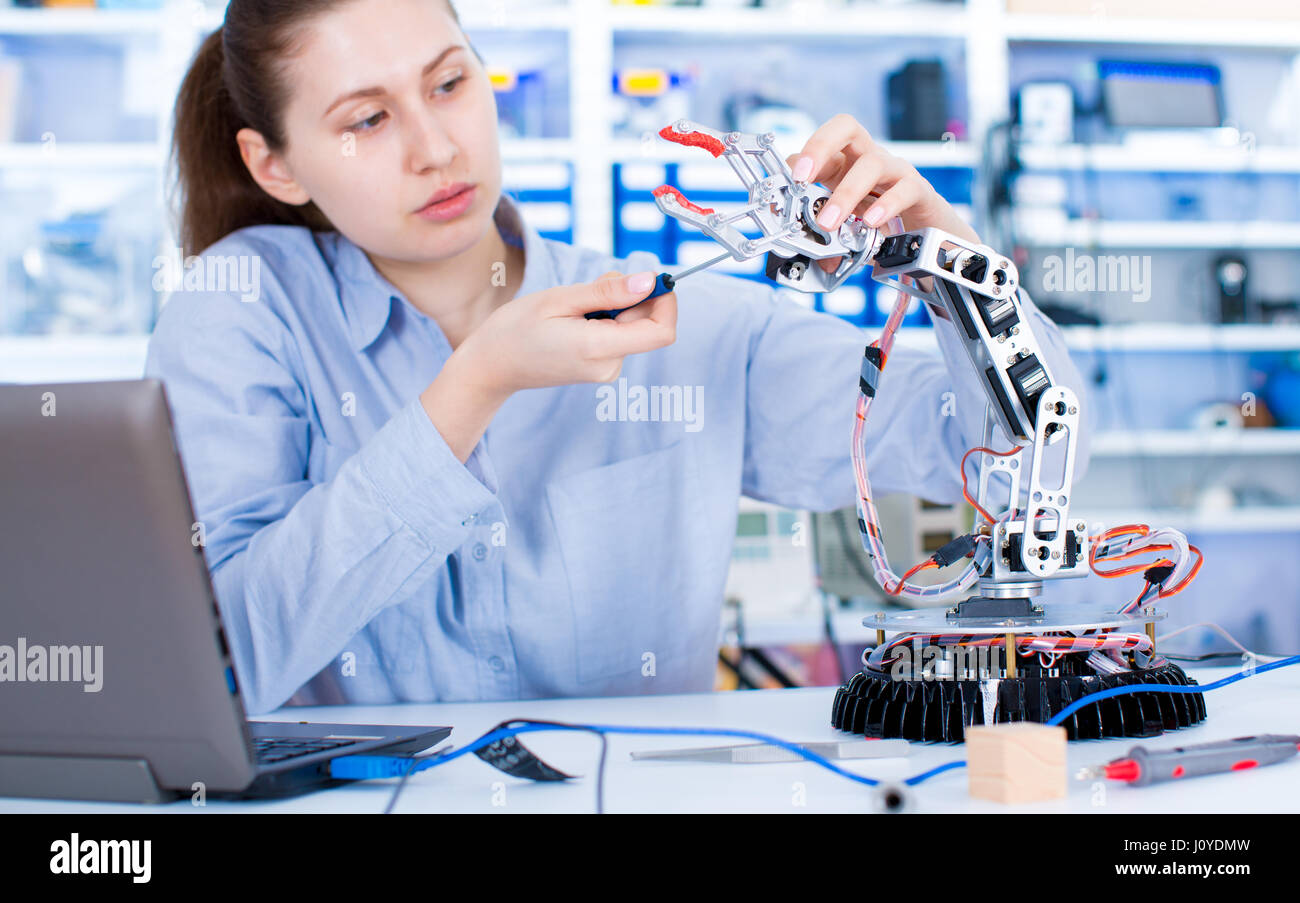 Girl in robotics laboratory. Young woman technician repair roboter ...