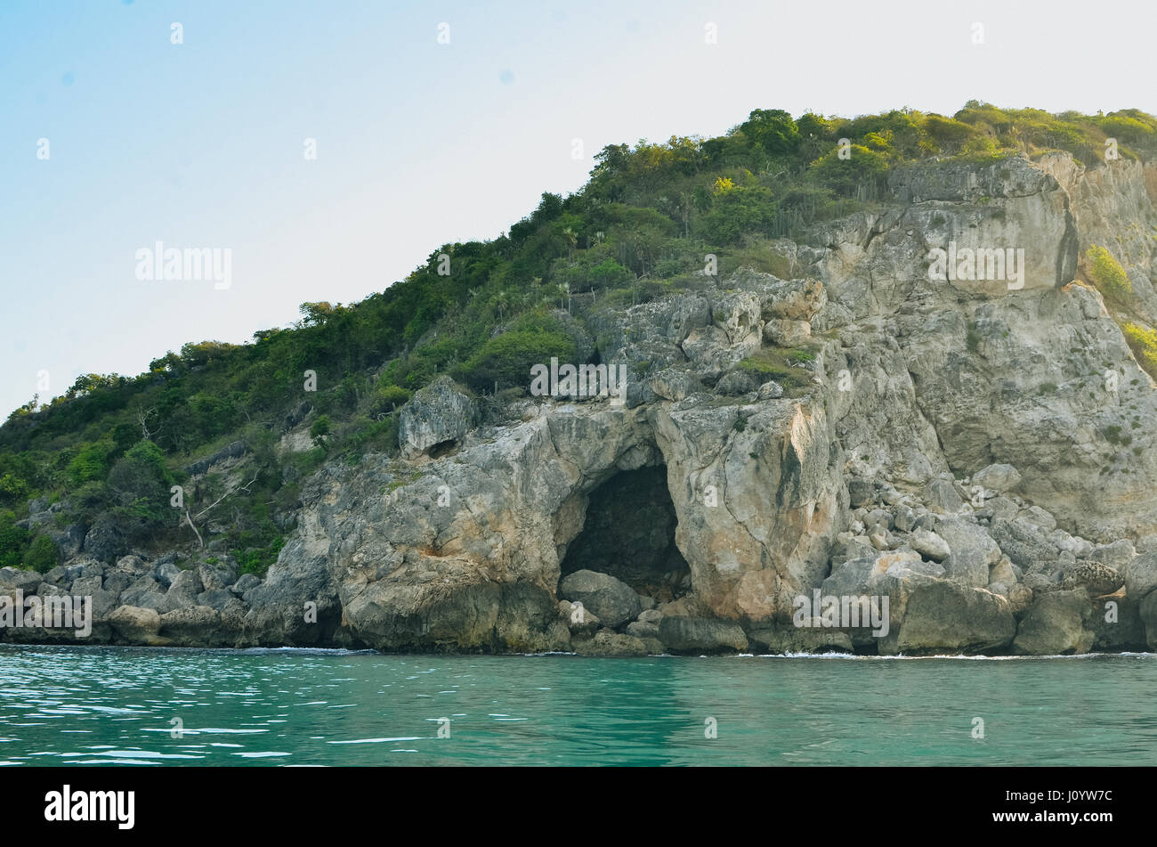 This photo was taken from a boat. There is cliffs with a cave. There ...
