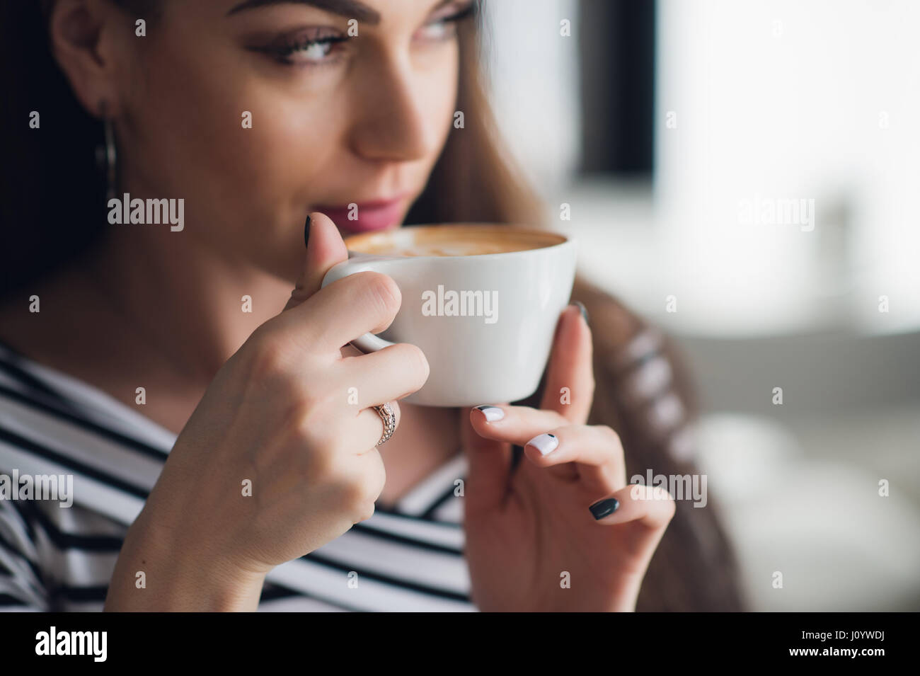 Close up picture of hands holding a cup and woman drinking coffee from ...