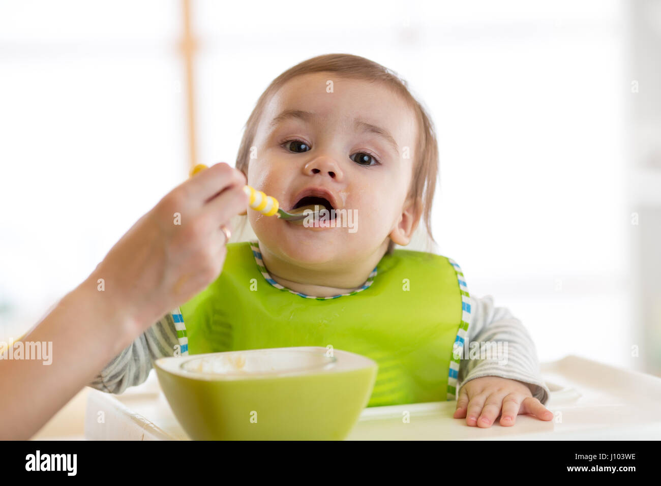 Baby eating food with mother help at home Stock Photo - Alamy