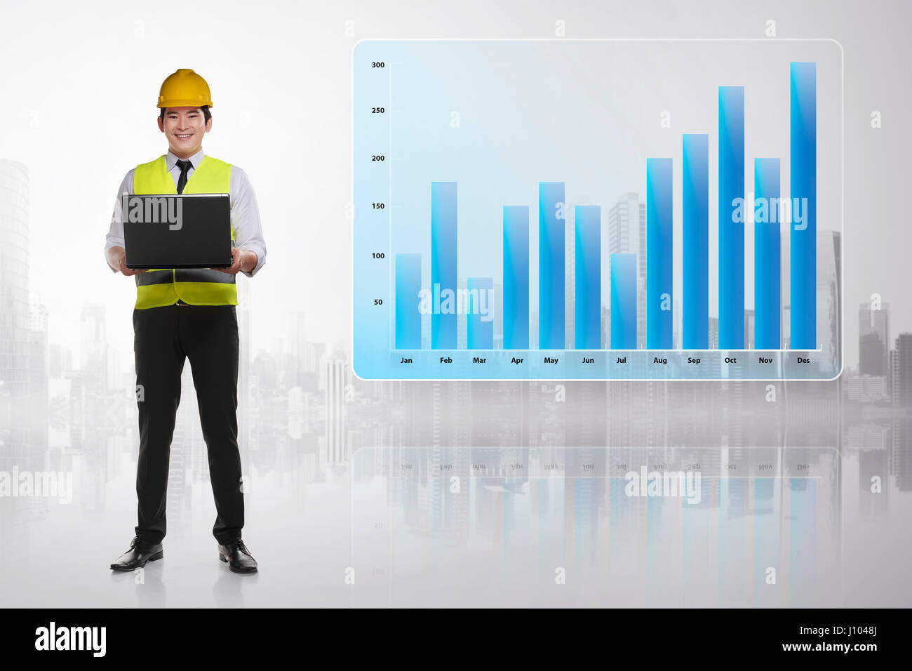 Young asian engineer man with laptop standing beside income graph on ...