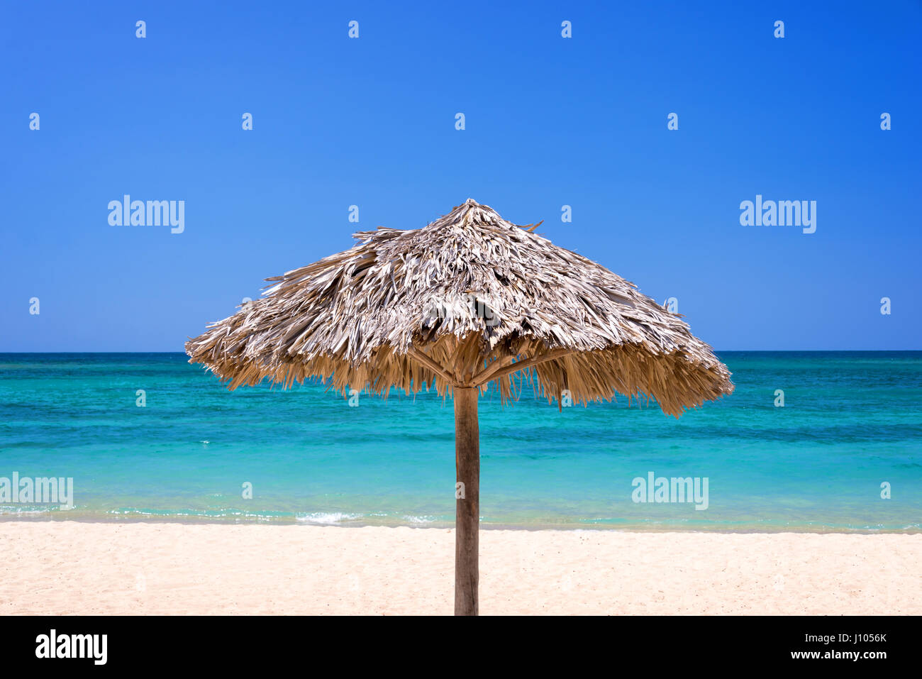 Straw umbrella on a beautiful tropical beach Stock Photo - Alamy