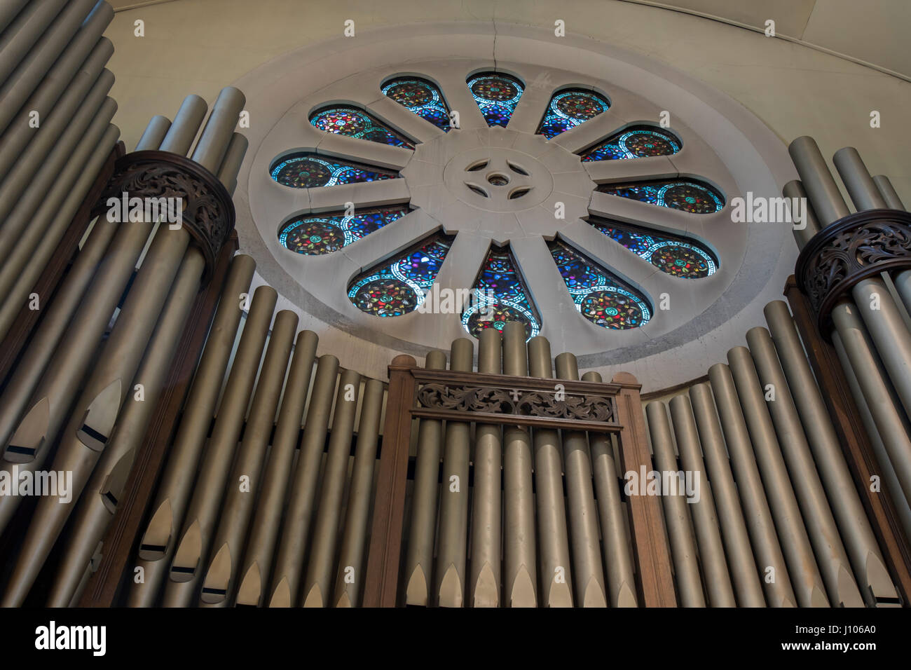 Stained glass window over metal organ pipes inside abandoned church ...