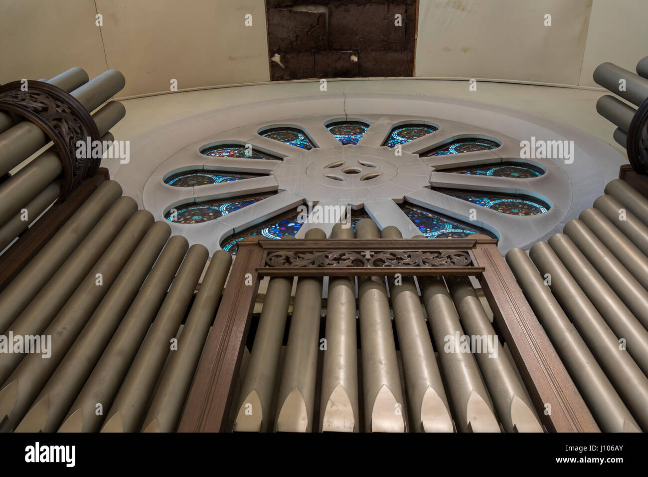 Stained glass window over metal organ pipes inside abandoned church ...