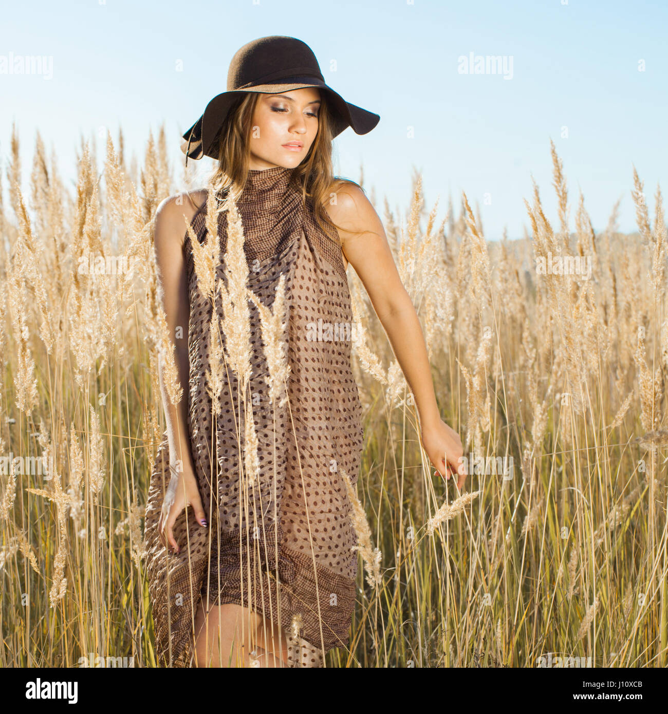Model in hat walking through tallgrass - outdoors shot Stock Photo - Alamy