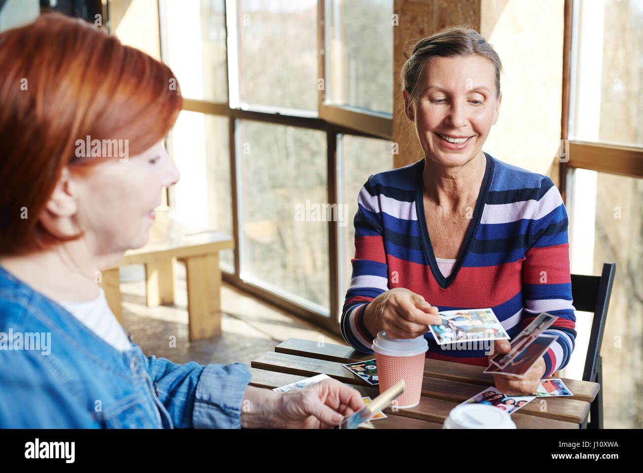Two retired females discussing photos during coffee break Stock Photo ...
