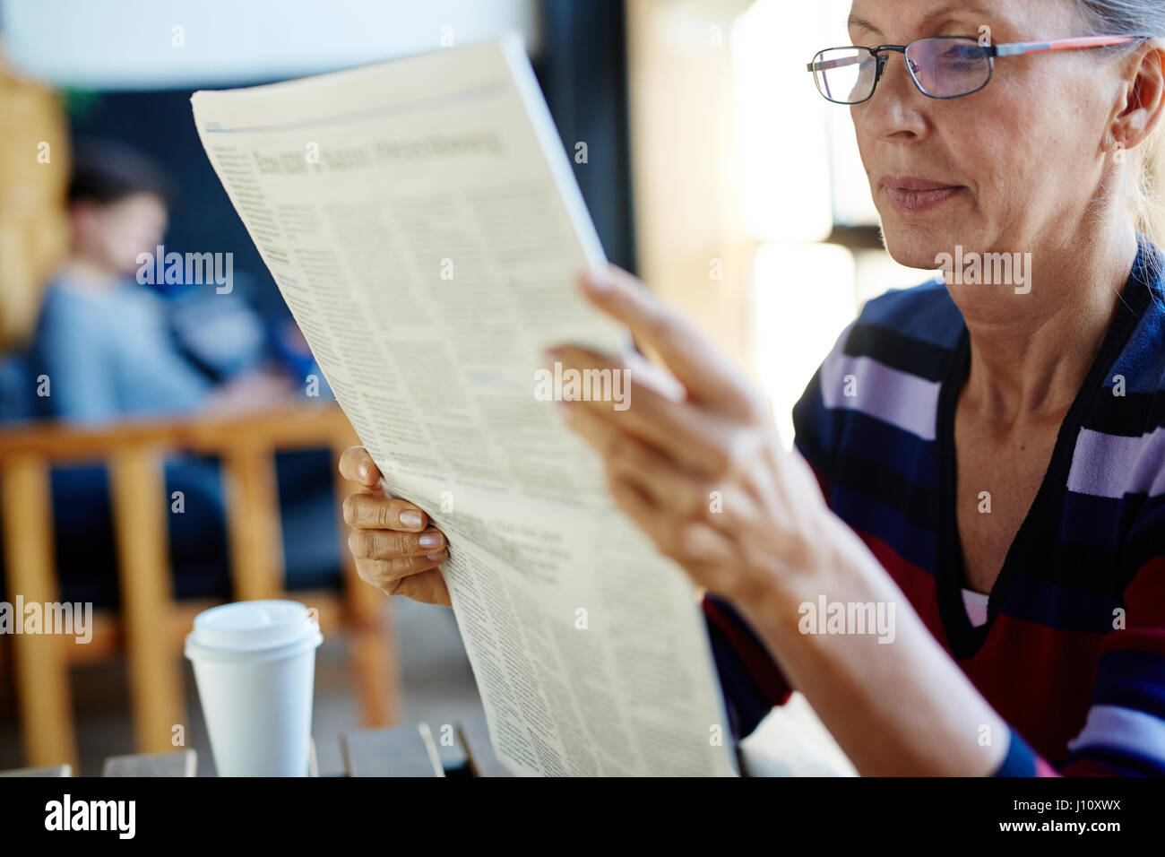 Serious mature female concentrating on reading news Stock Photo - Alamy