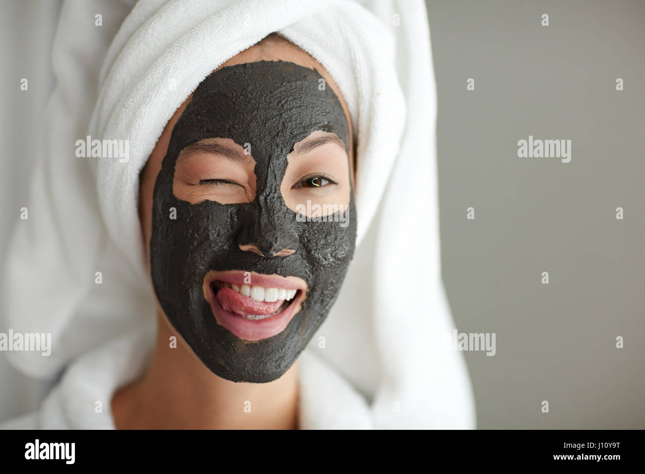 Flirty girl winking while having purifying mask Stock Photo - Alamy