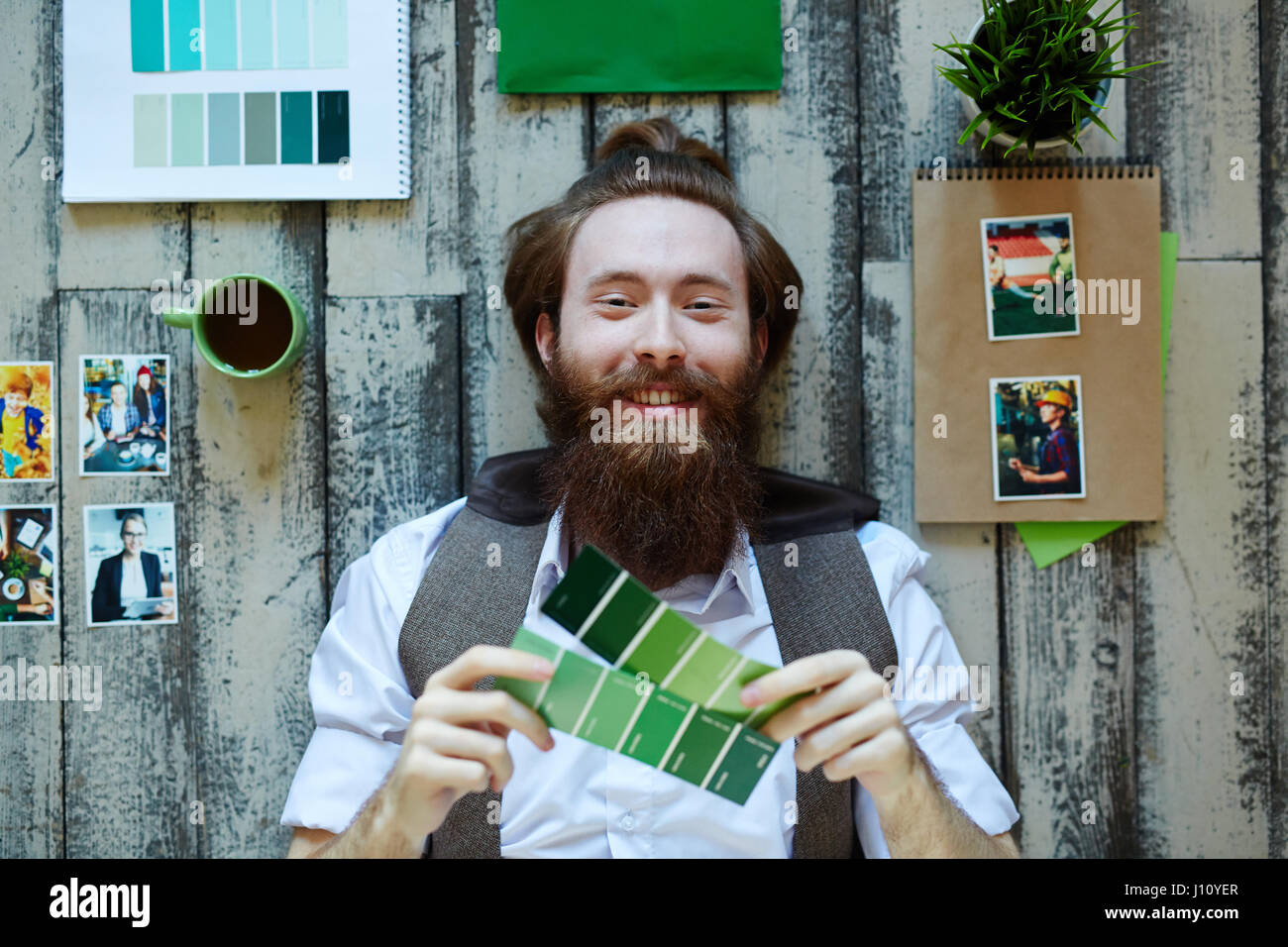 Happy bearded man with green color swatches lying on the floor Stock ...