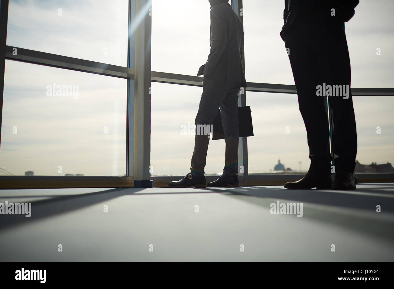 Outlines of humans in suits standing by office window Stock Photo - Alamy