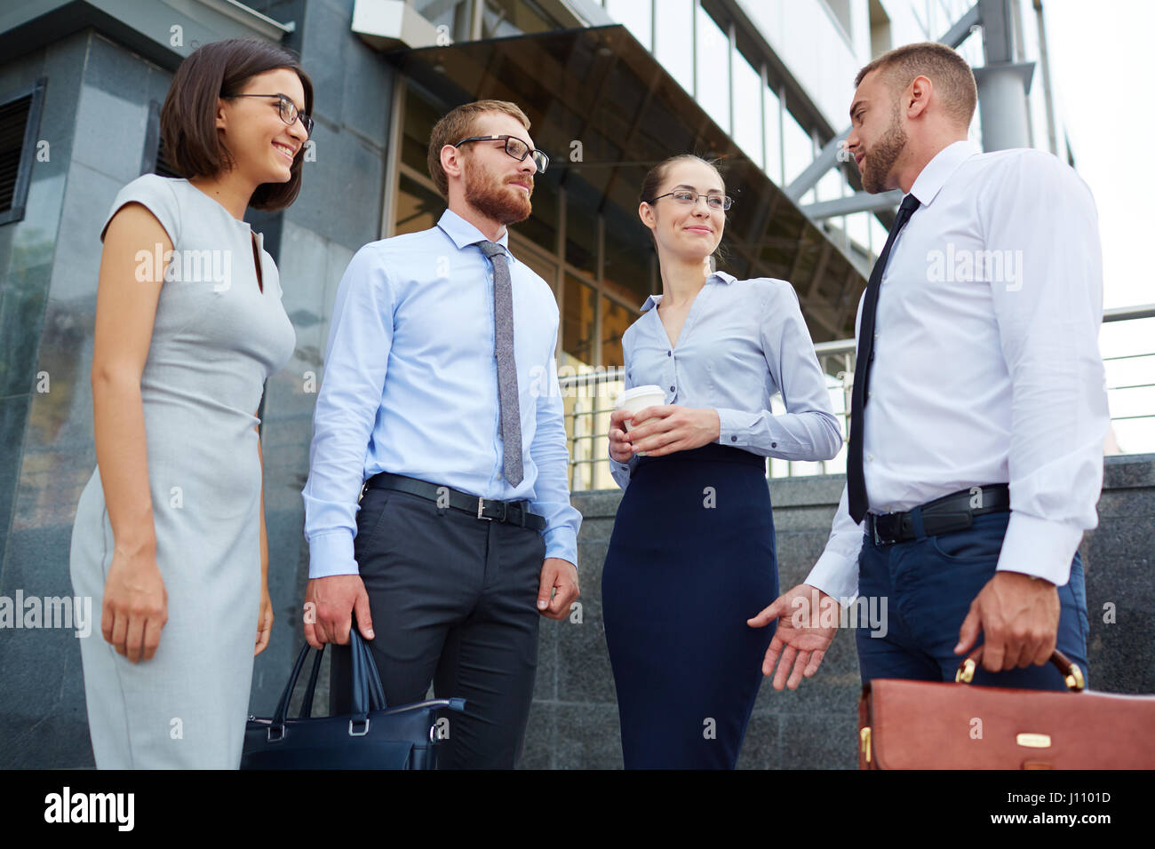 Group of young successful business people chatting outside modern ...