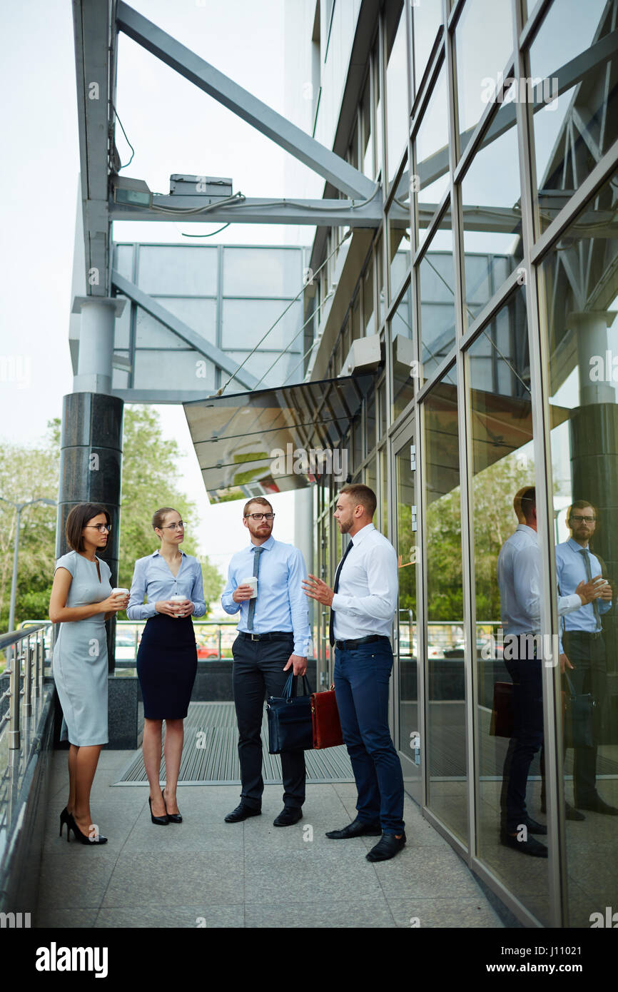Group of young successful business colleagues discussing work outside ...