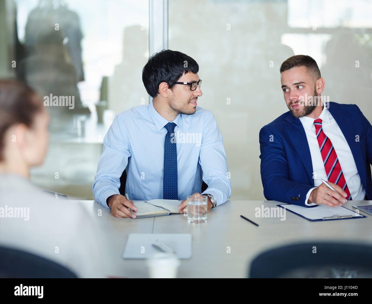 Portrait of two young business people leaning to each other while ...
