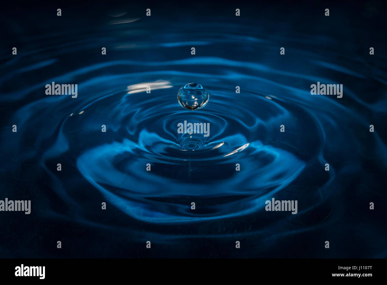 Water drop an waves with blue background and reflection Stock Photo - Alamy