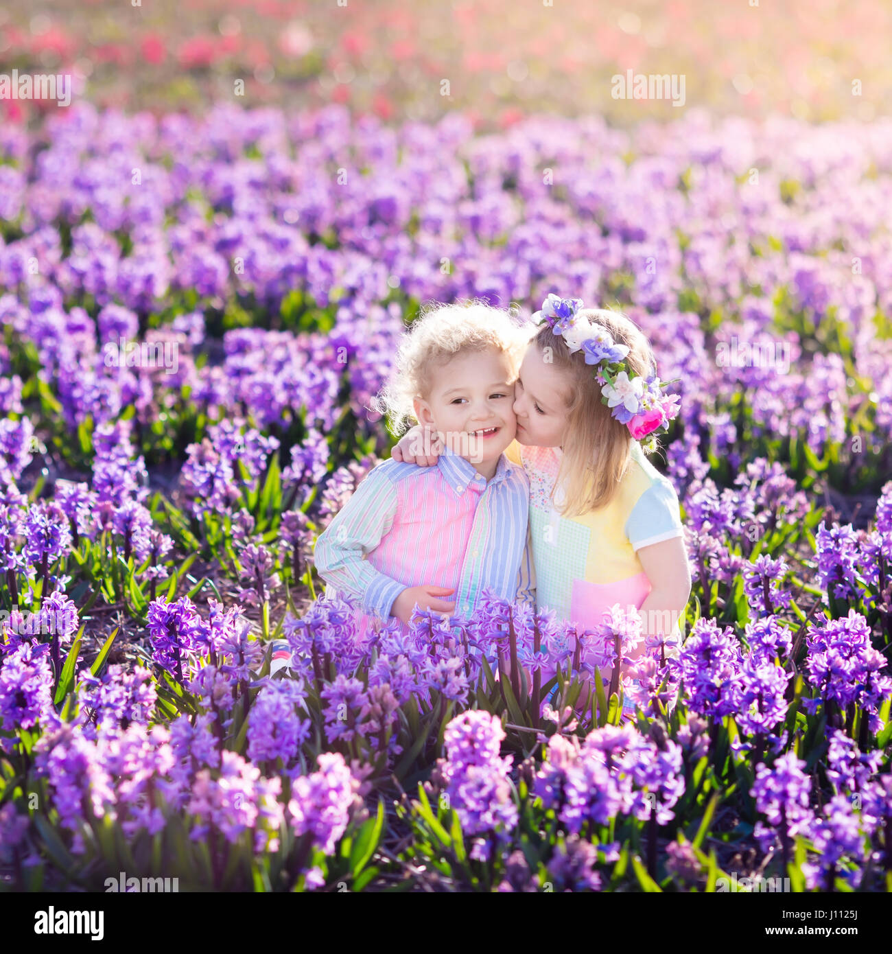 Kids gardening. Children play outdoors in hyacinths meadow. Little girl ...