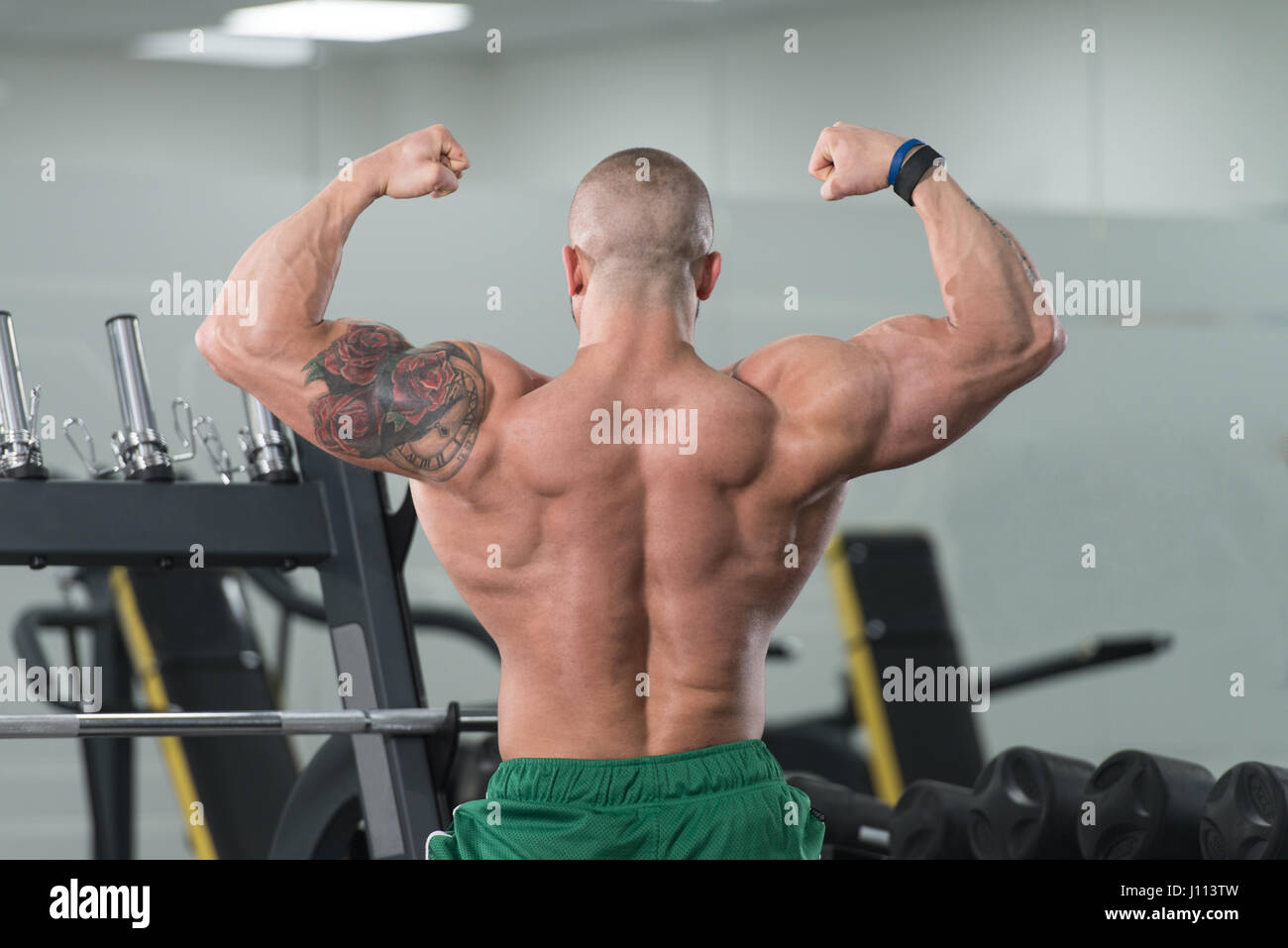 Healthy Young Tattoo Man Standing Strong In The Gym And Flexing Muscles ...