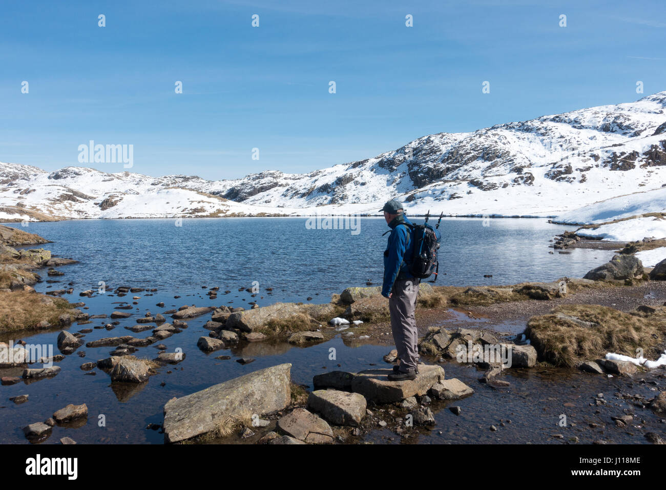 A lone walker at Sprinkling tarn in the English Lake District Stock ...