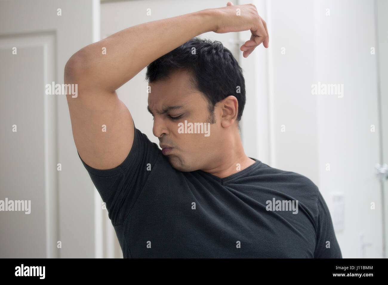 Closeup portrait, grumpy sweaty young man in black t-shirt, sniffing ...