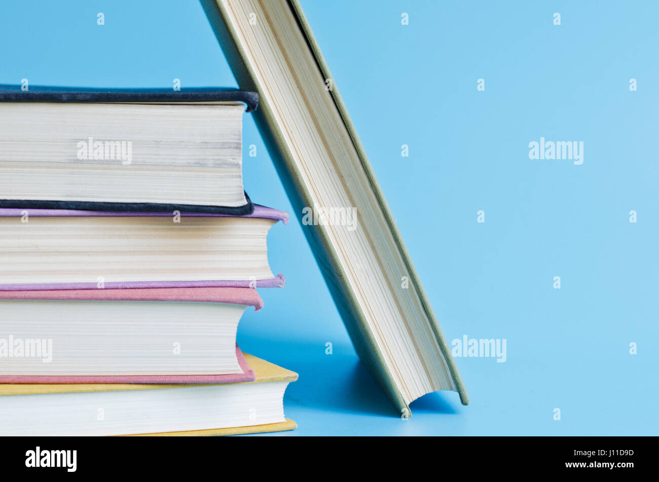 a stack of colorful books on a blue background in library Stock Photo ...