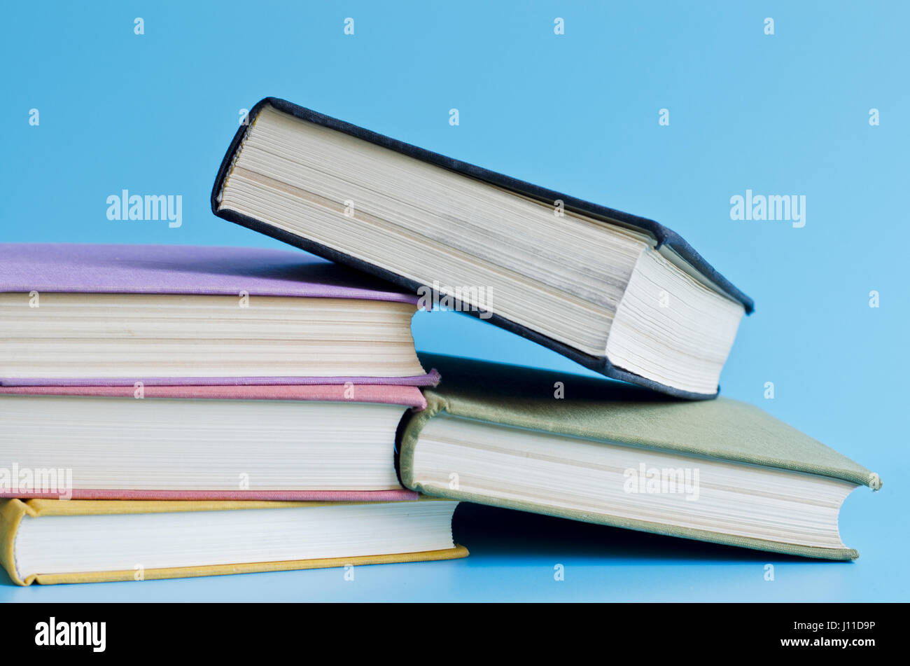 a stack of colorful books on a blue background in library Stock Photo ...