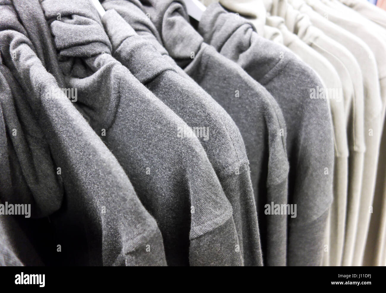 Gray clothes on hangers in store Stock Photo - Alamy