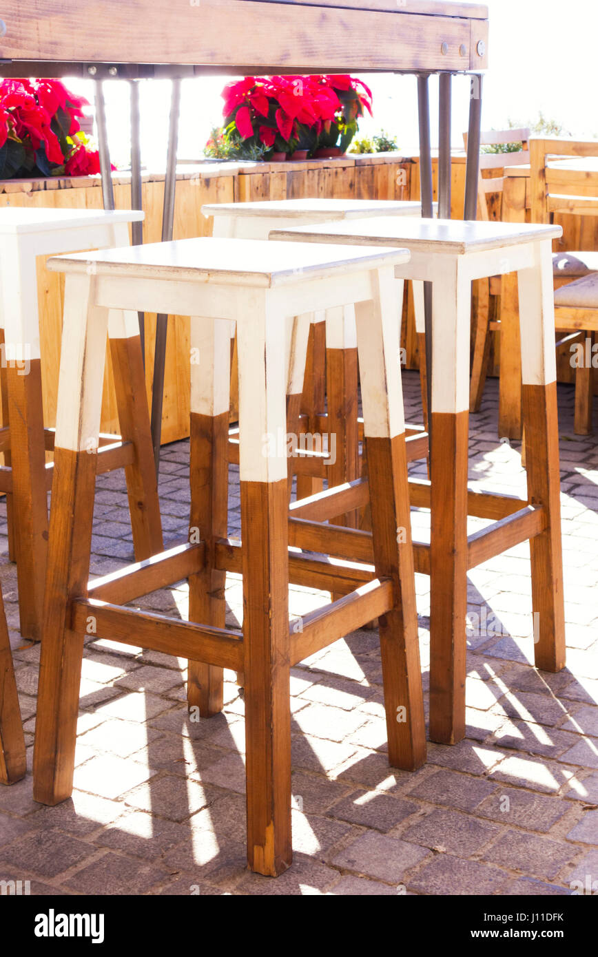 High wooden bar stools standing on the open terrace of the restaurant ...