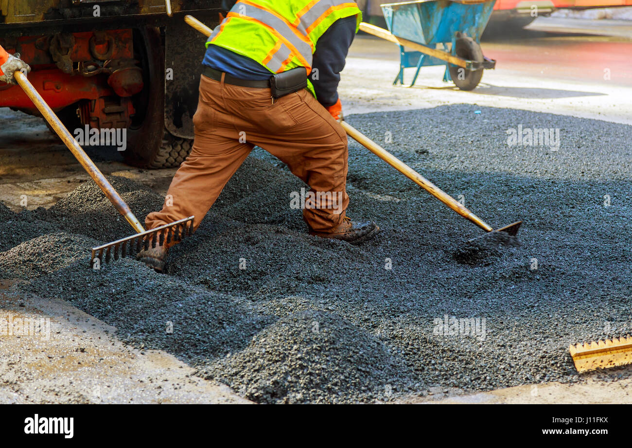 Men at work, urban road under construction, asphalting in progress ...