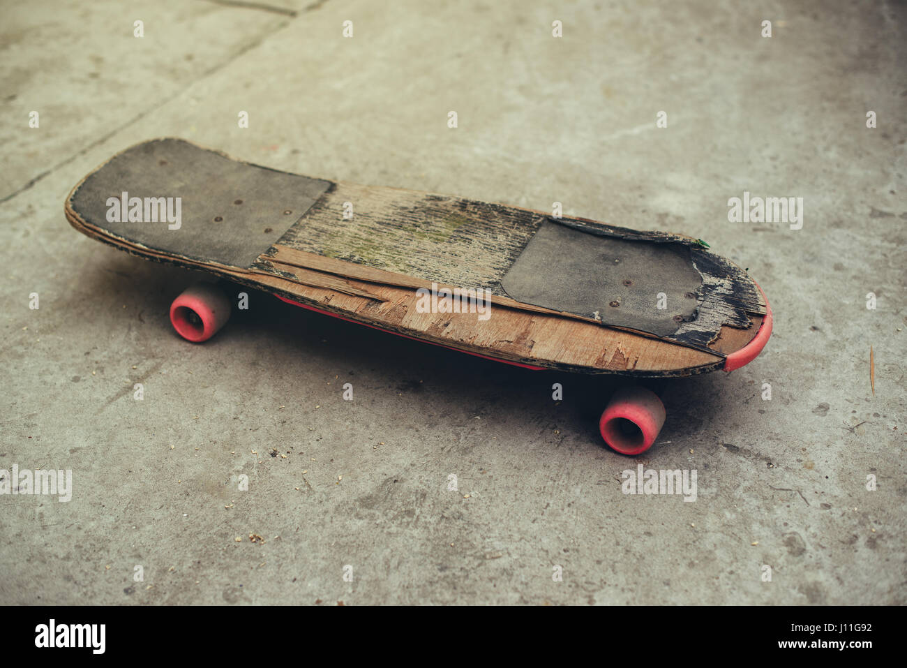 Old weathered skateboard on concrete surface, abandoned in skate park ...