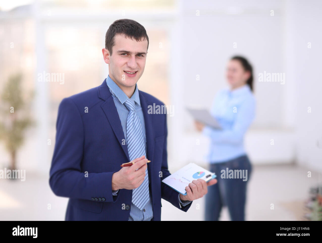 Happy young businessman reading paperwork at in office Stock Photo - Alamy