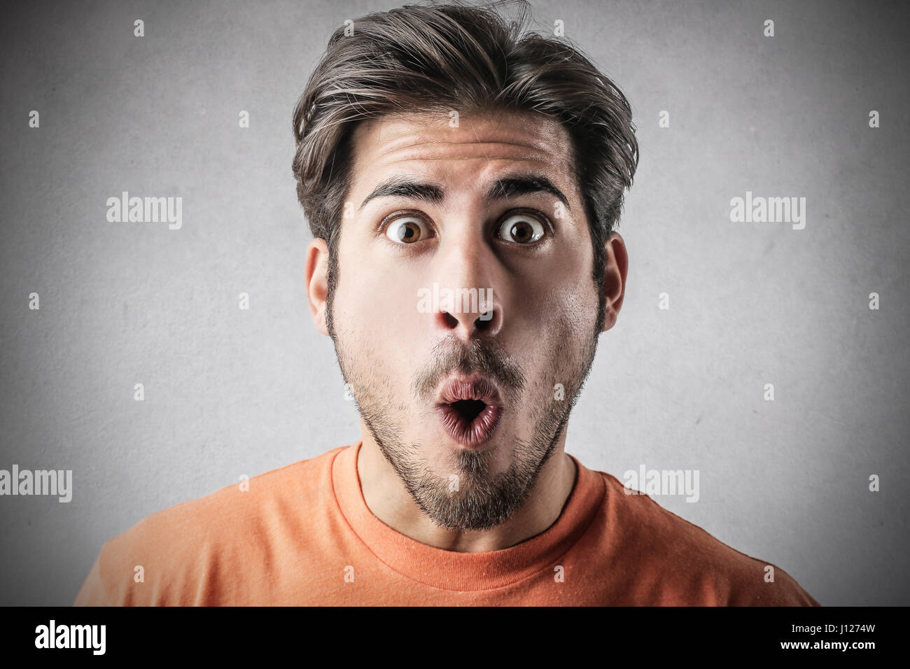 Man in orange shirt being surprised Stock Photo - Alamy
