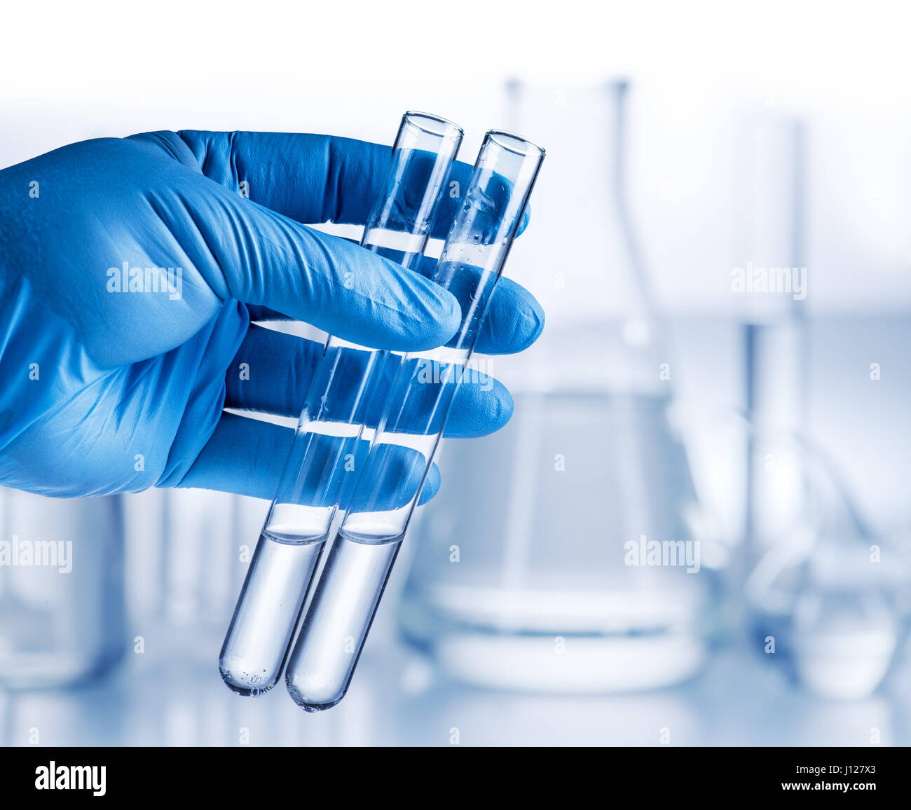 Laboratory beakers in analyst's hand in plastic glove Stock Photo - Alamy